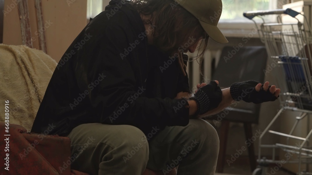 Homeless poor man sitting in a room of an abandoned building. He is ...