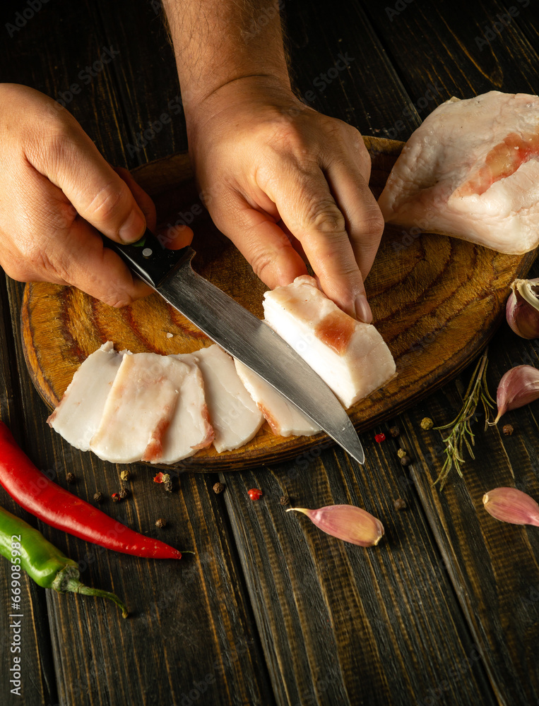 Cutting lard into small pieces for a snack in the hands of a chef with ...
