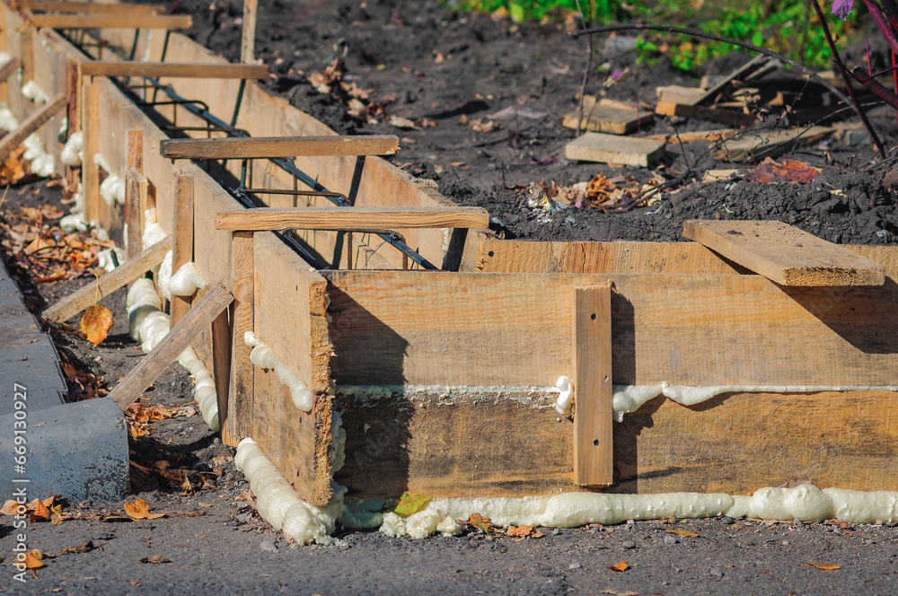 Along the edge of the sidewalk for pouring concrete, formwork made of ...