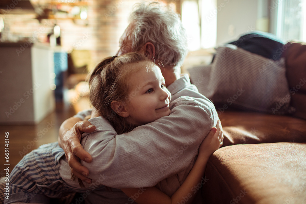 Little girl hugging her grandfather in the living room Stock Photo ...