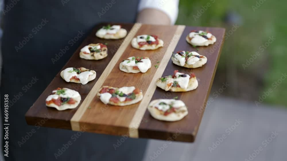 A close-up shot of a tray of pizzas. The person is wearing a uniform ...