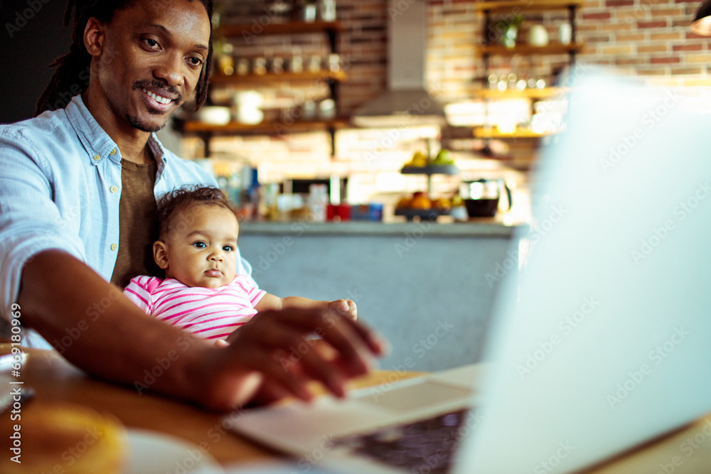 Doting father multitasking with work and baby in a modern kitchen Stock ...