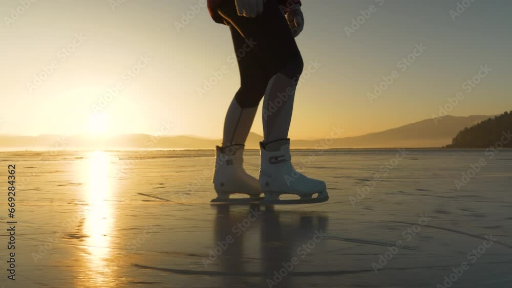 CLOSE UP, LENS FLARE, SILHOUETTE: Lady skating on frozen lake in early ...