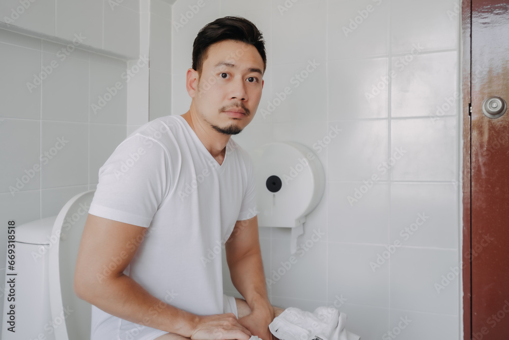 Funny face asian man pushing poop in the toilet as he has constipation ...
