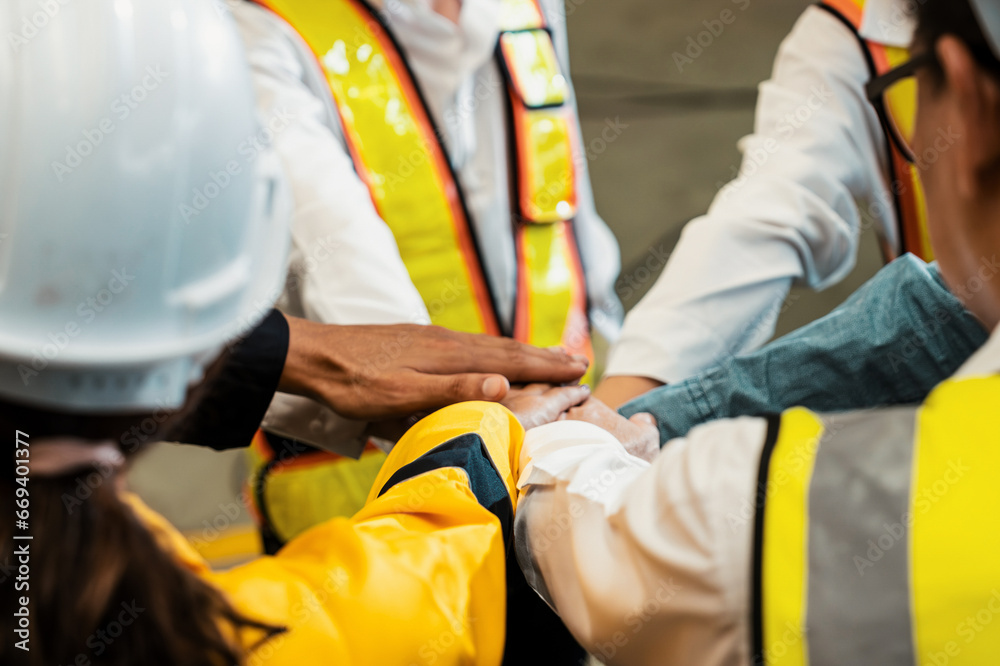 Cohesive and united group of factory worker joining hands together in ...