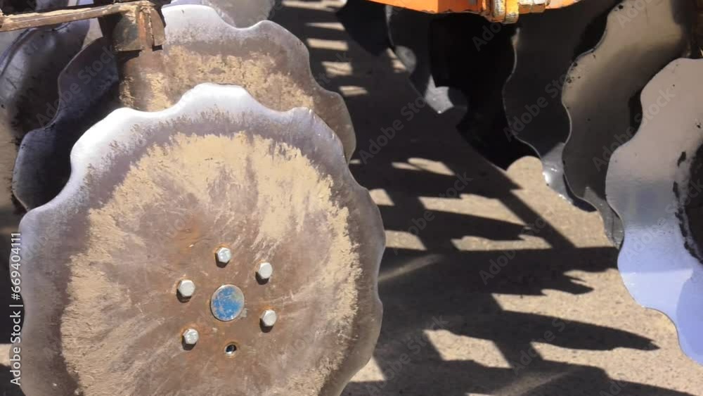 Close up of a disc harrow system, cultivate the soil. Tractor plows the ...