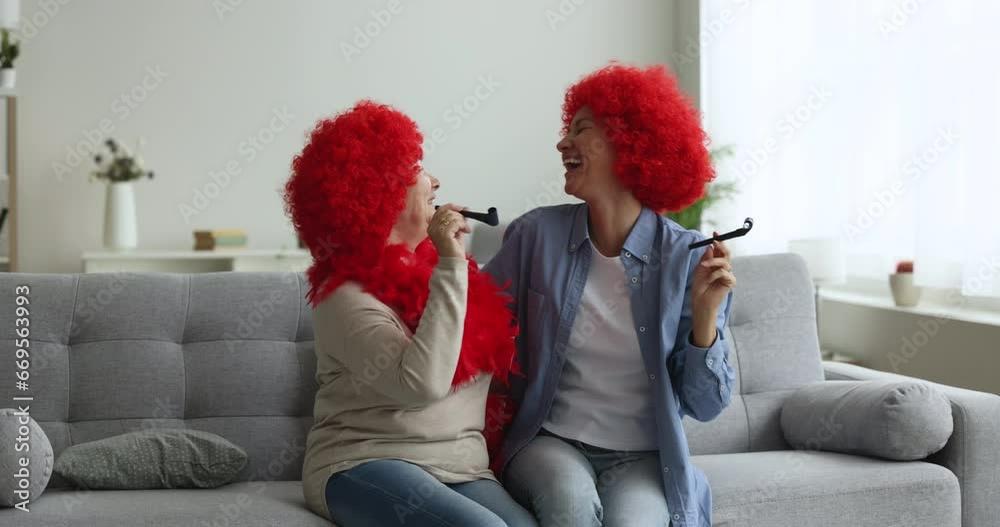 Joyful senior mother and adult daughter woman wearing red clown wigs ...
