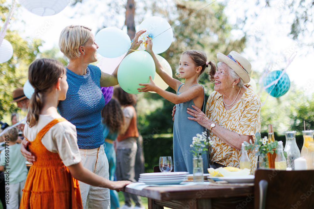 Grandmother, mother and daughters setting decorations for summer garden ...