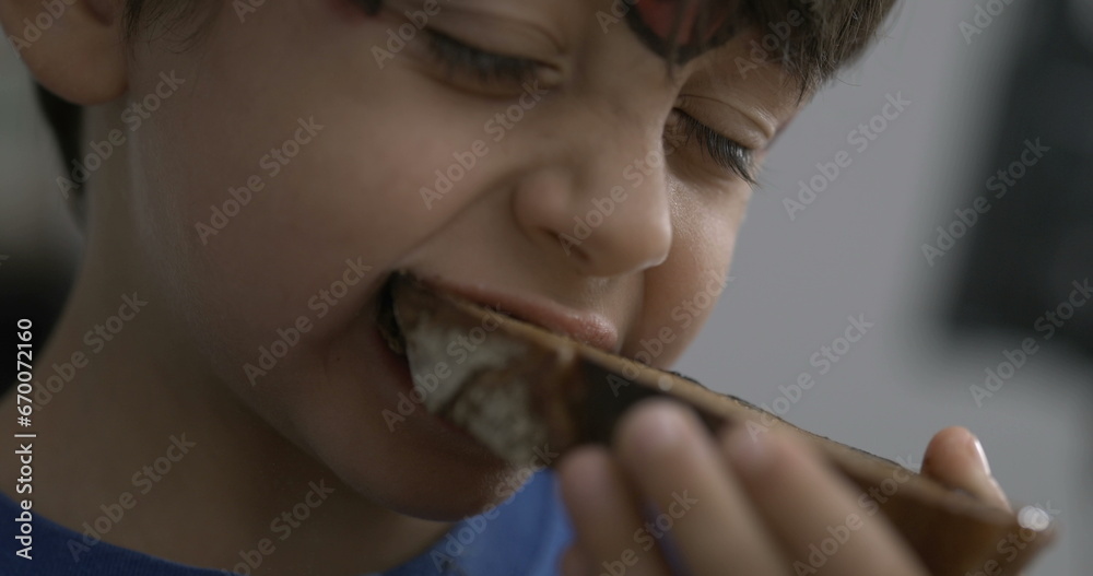 One small boy taking a bite of toast bread, close-up child mouth eating ...