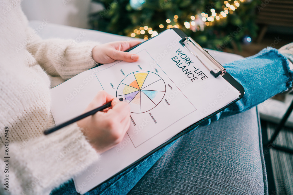 Woman drawing work-life balance wheel sitting on the sofa at home. Self ...