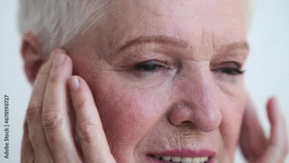 Vidéo Stock Elderly woman gently touches face with a smile of ...