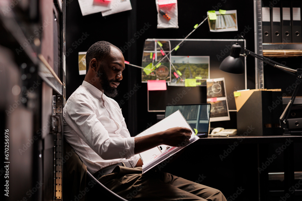 African american detective studying crime case file before conducting ...
