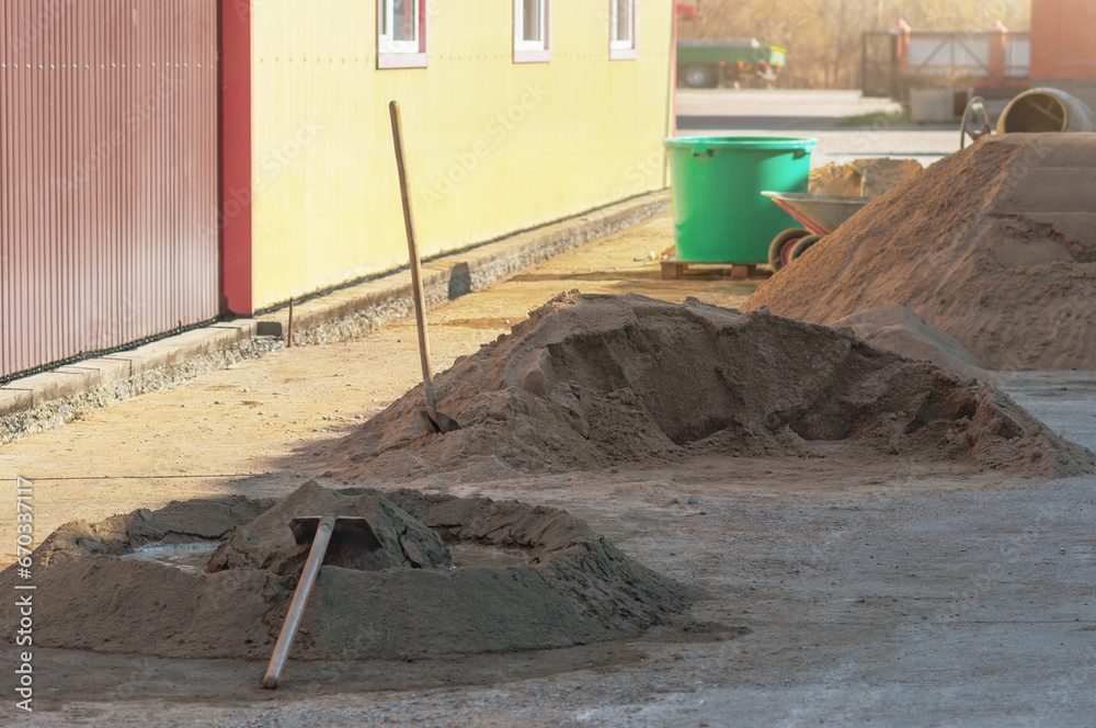 Heaps of sand and cement on a construction site next to the garage ...