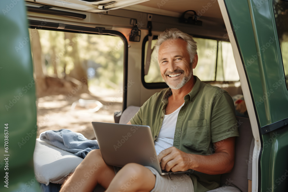 Happy older man sitting in rv camper van using laptop. Smiling mature ...