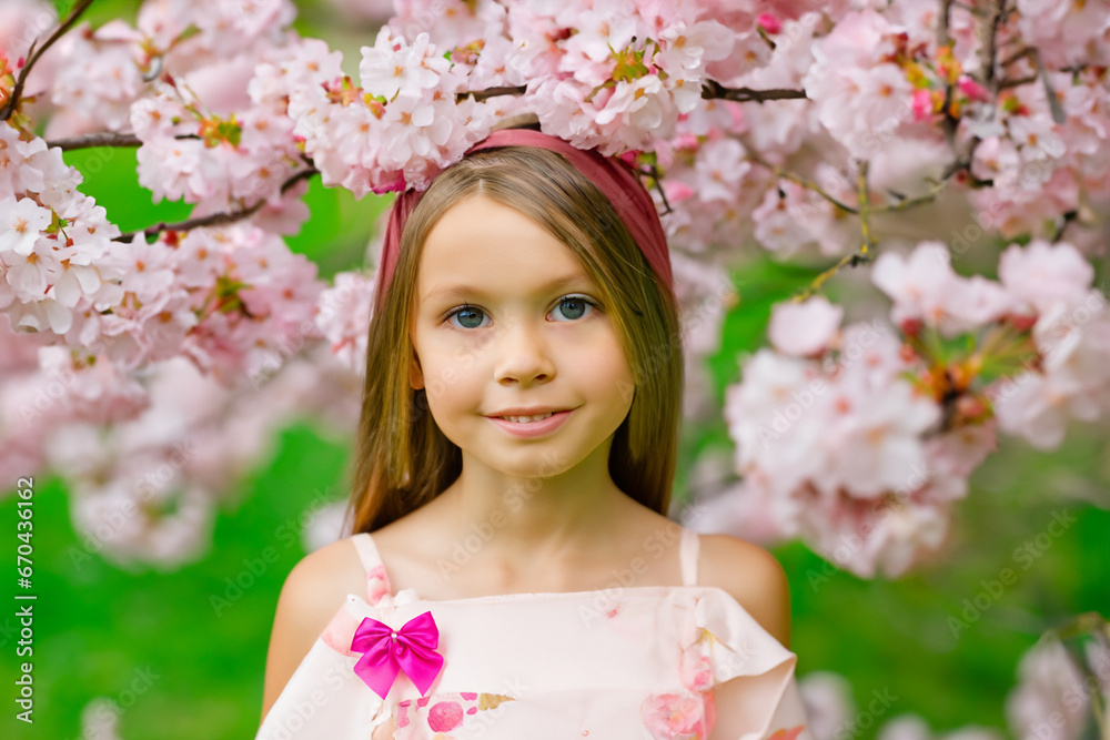 little girl with sakura tree. a beautiful young girl stands in a ...