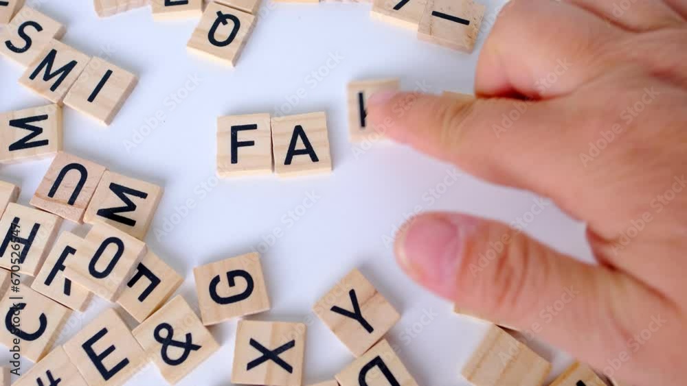 female hand close-up collecting word fake on table made of wooden ...