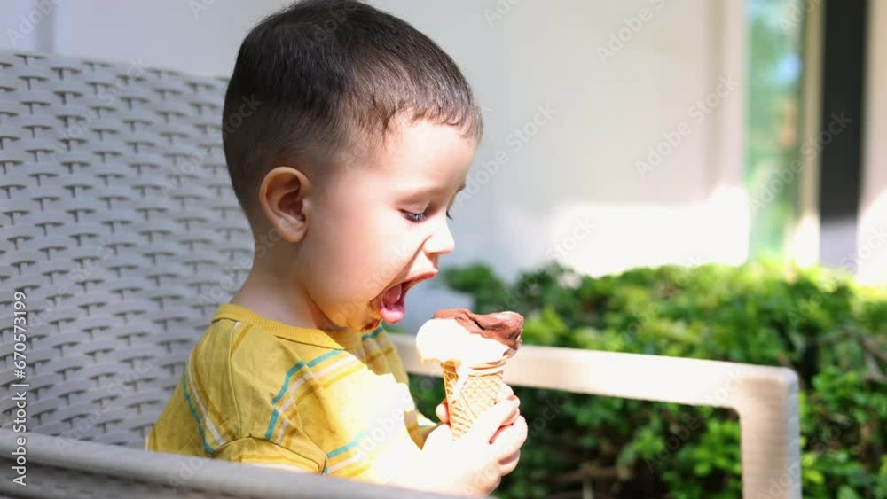 kid boy and baby eating ice cream in cone sitting on chair outdoor ...