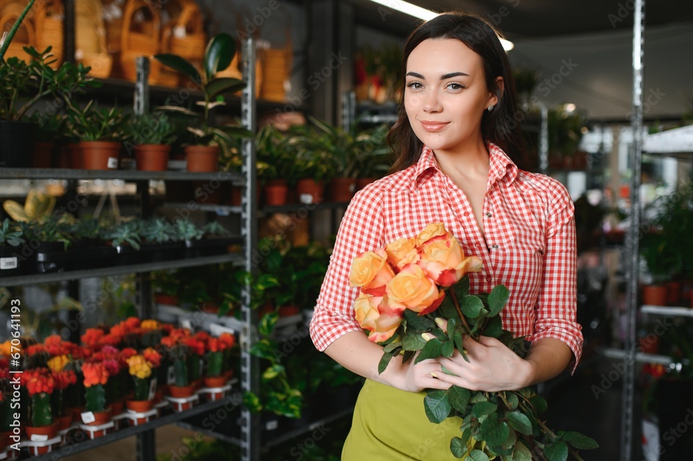 Cute girl florist collects a bouquet of roses in a flower shop. A ...