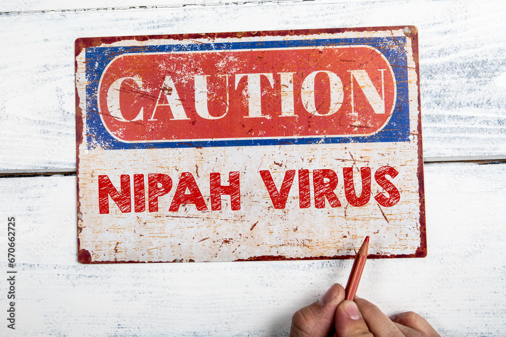 Nipah Virus. Metal CAUTION plate with text on a white wooden background ...