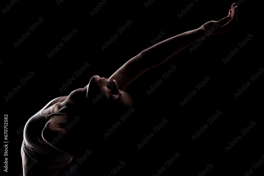 Beautiful caucasian girl posing yoga and stretching in shadow. side lit ...