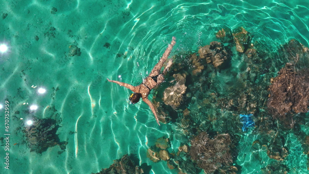 Aerial top down woman snorkeling in crystal sea water enjoy coral reef ...