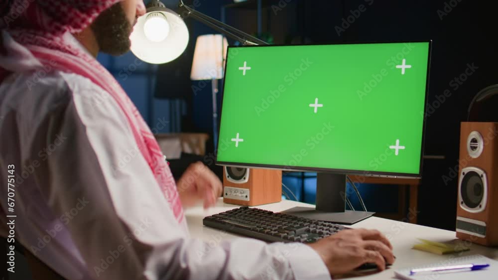 Muslim worker looking at chroma key computer screen while working from ...