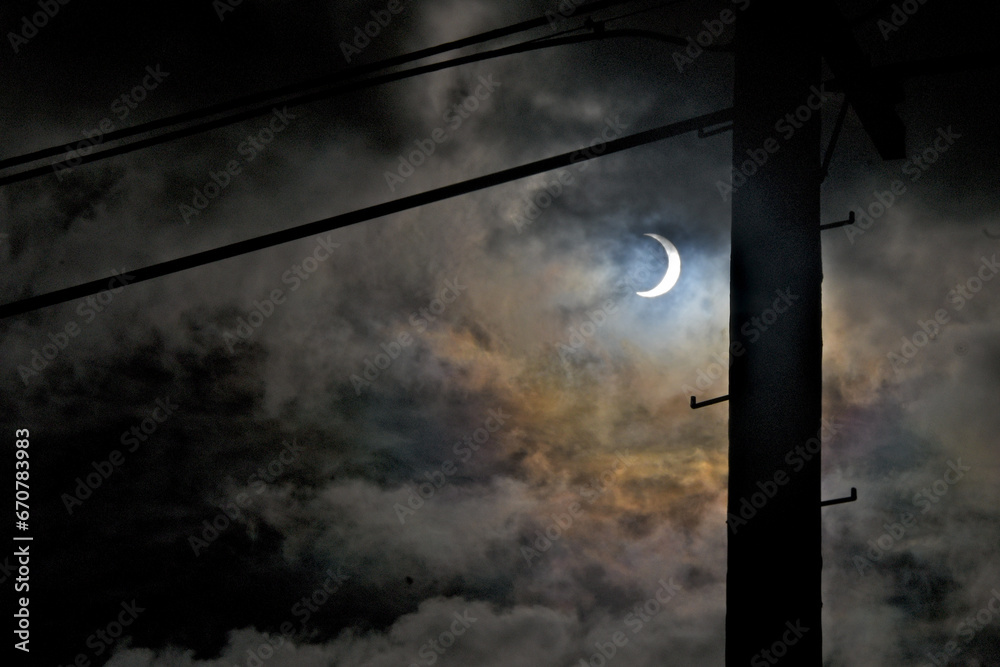 Partial Eclipse and diffraction corona silhouette power pole and cable ...