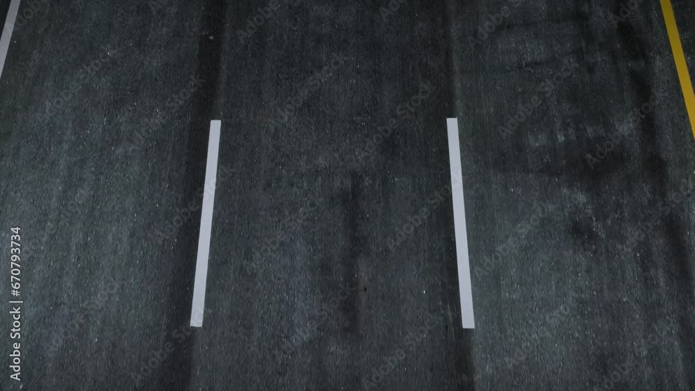 A close-up view of the asphalt road surface as a sleek car smoothly ...
