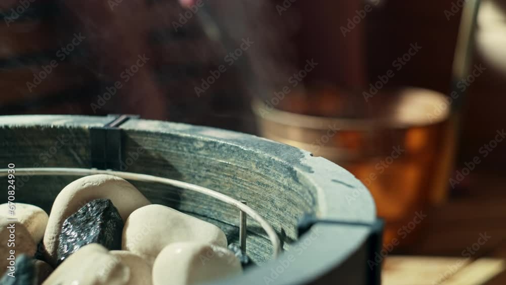 Throwing water on hot sauna stones in sauna stove, using a scoop or ...