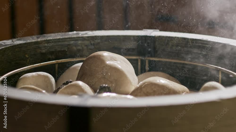 Vidéo Stock Throwing water on the sauna stones in the sauna stove ...