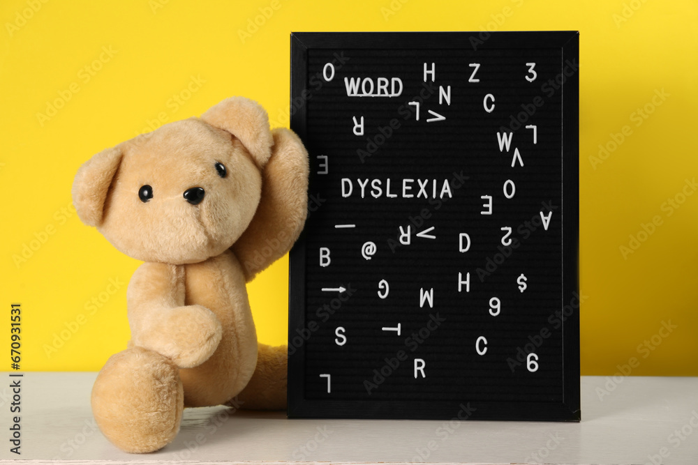 Black letter board with word Dyslexia and teddy bear on light table ...