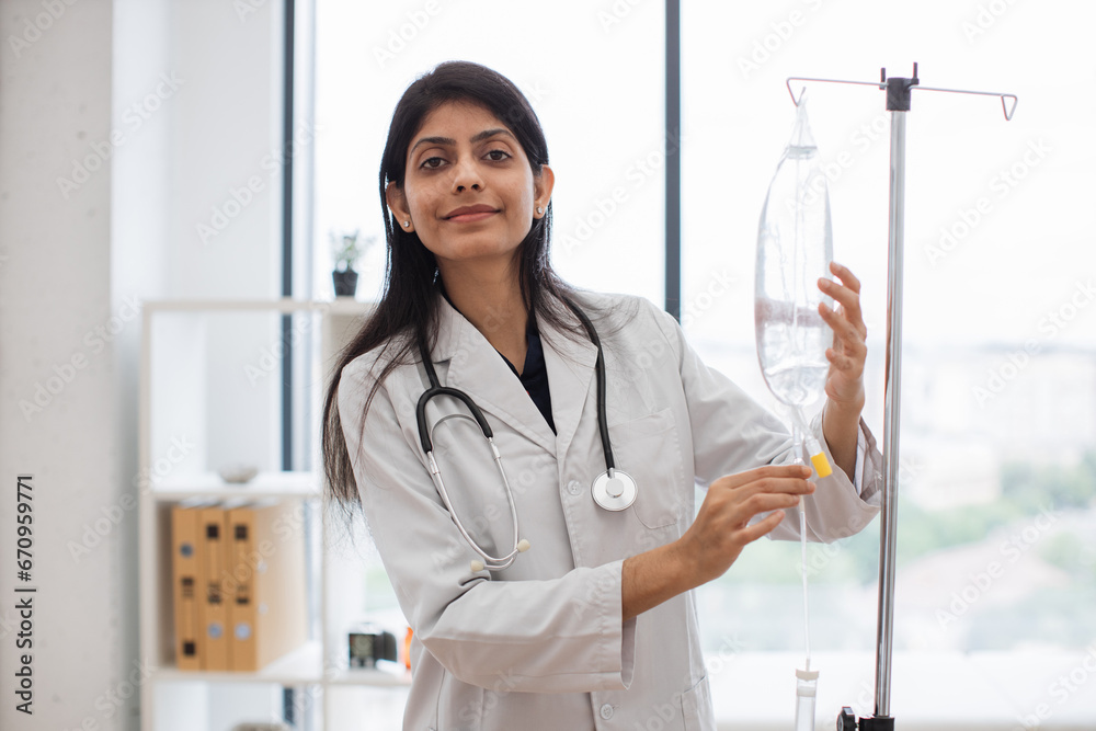 Adult female doctor in white lab coat standing near medical dropper and ...
