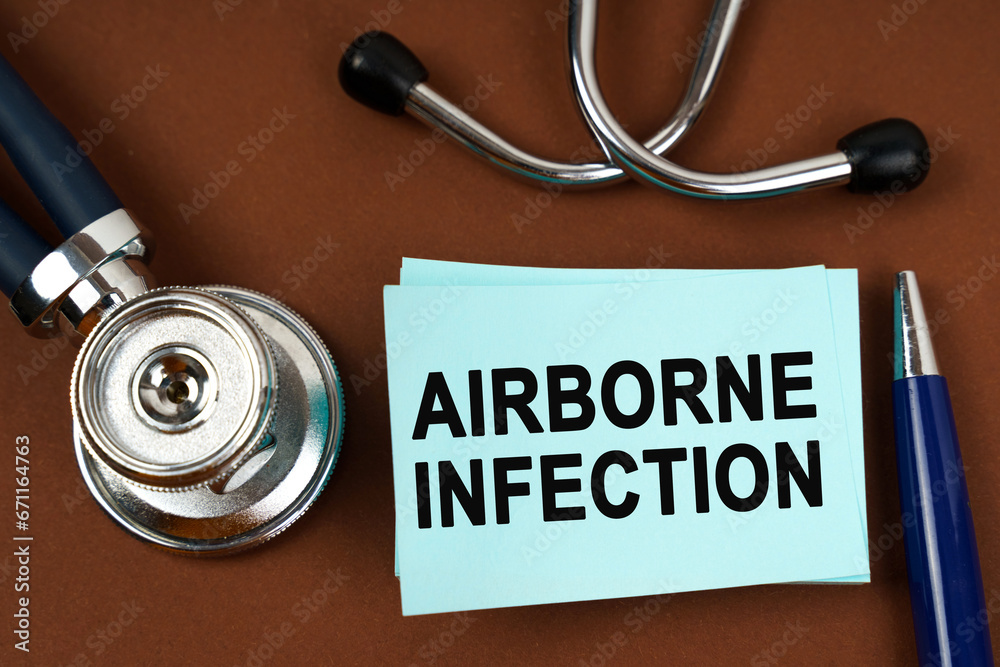 On a brown surface there is a stethoscope, a pen and blue stickers with ...