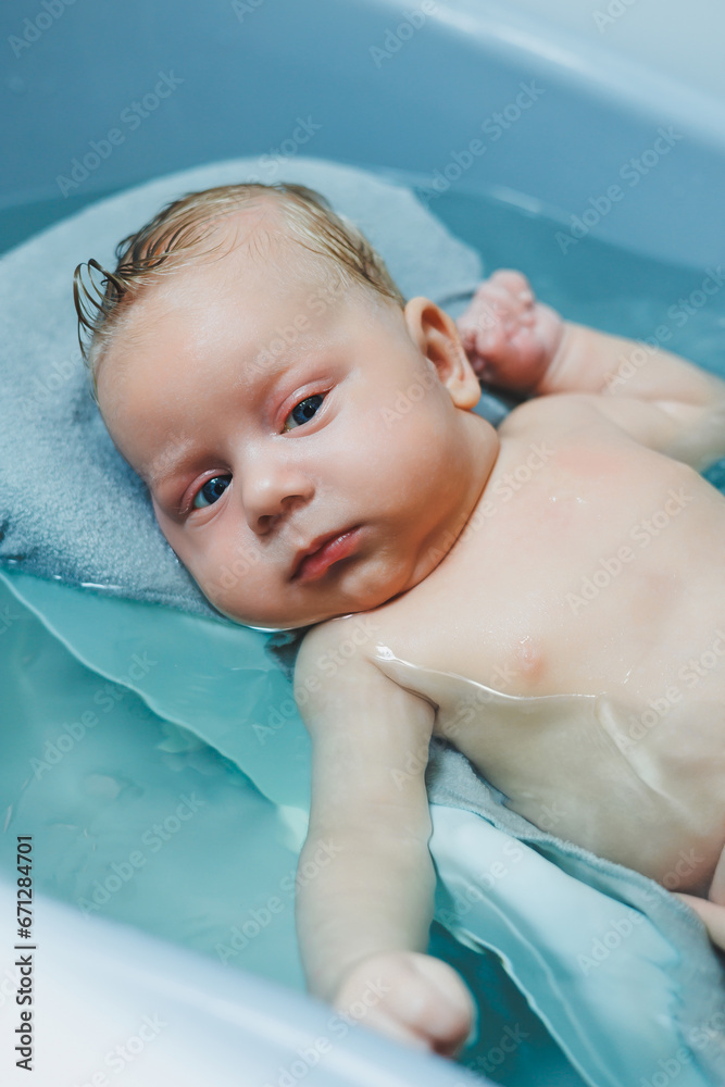 Bathing a baby in a baby bath. The first bath of a newborn baby. A baby ...