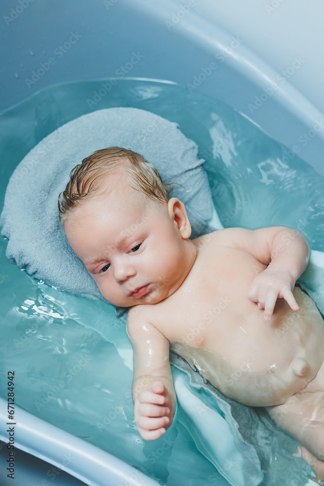 Bathing a baby in a baby bath. The first bath of a newborn baby. A baby ...