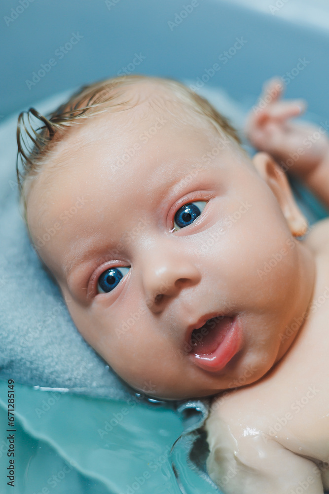 Bathing a baby in a baby bath. The first bath of a newborn baby. A baby ...
