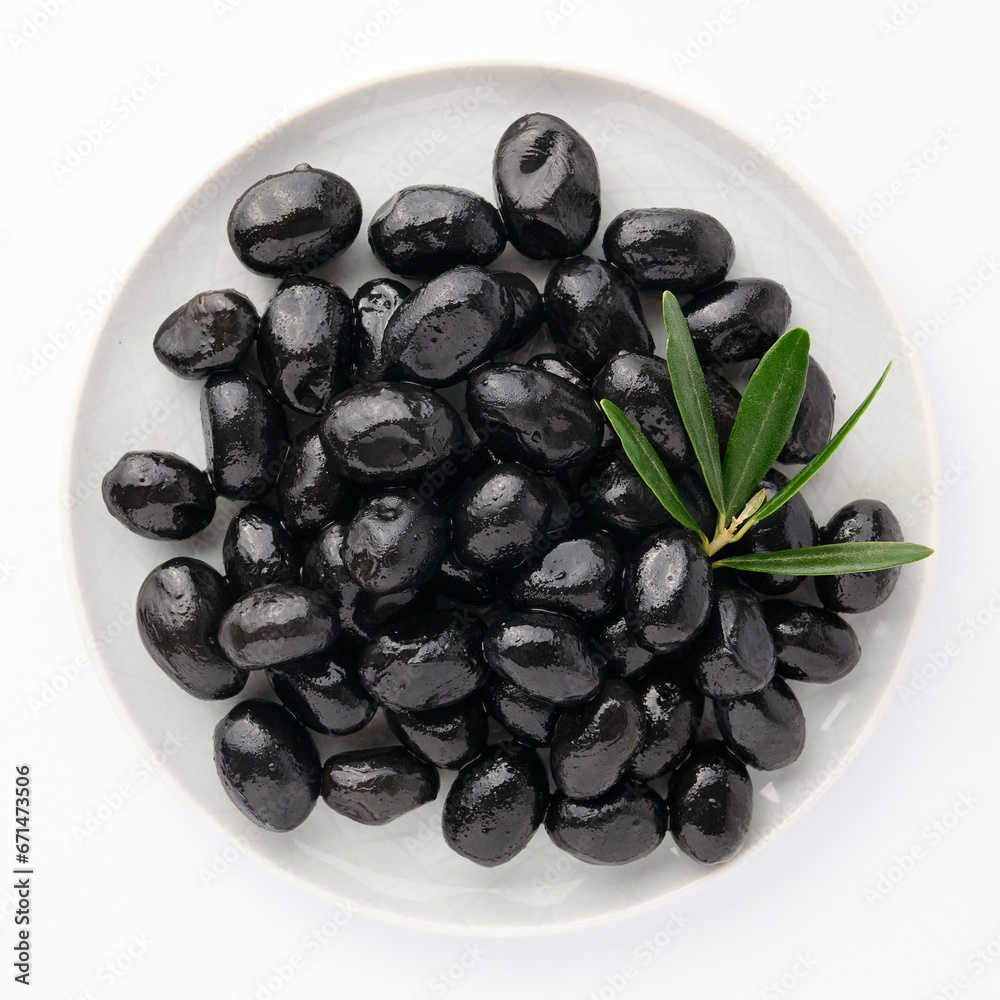 Delicious black olives in plate with olive tree sprig decoration ...