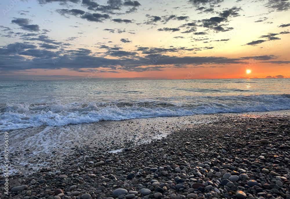 Pebble stone beach on sunrise. Sea beach shore with waves in ocean ...