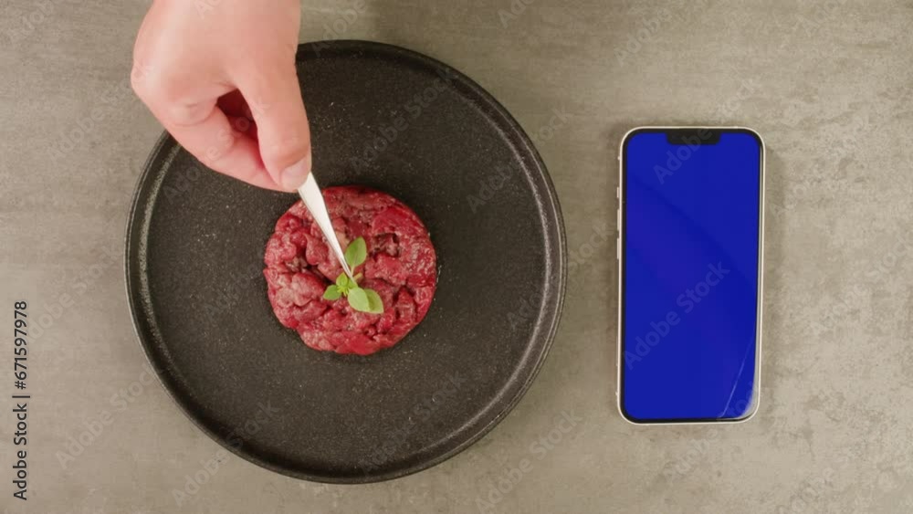 Phone with chroma key green screen with meat beef tartare on black ...