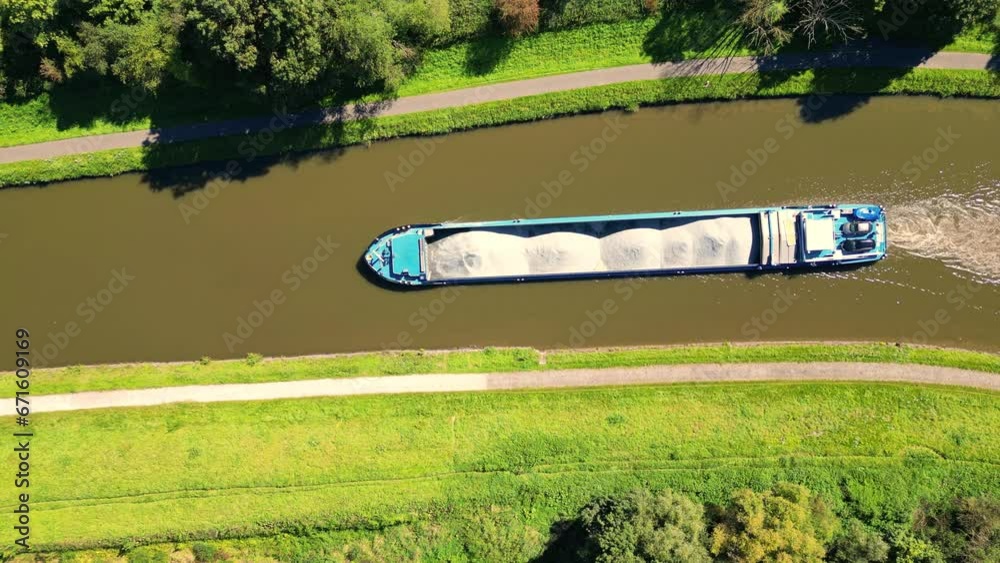 Suspended above, the camera captures a unique narrative: a hefty cargo ship, its deck filled ...