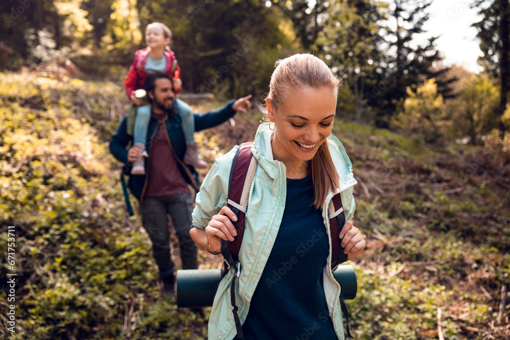 Joyful family hiking through the woods, with a child riding on her ...