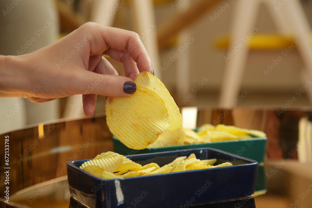 Young sad woman having unhealthy snack, eating potato chips in the ...