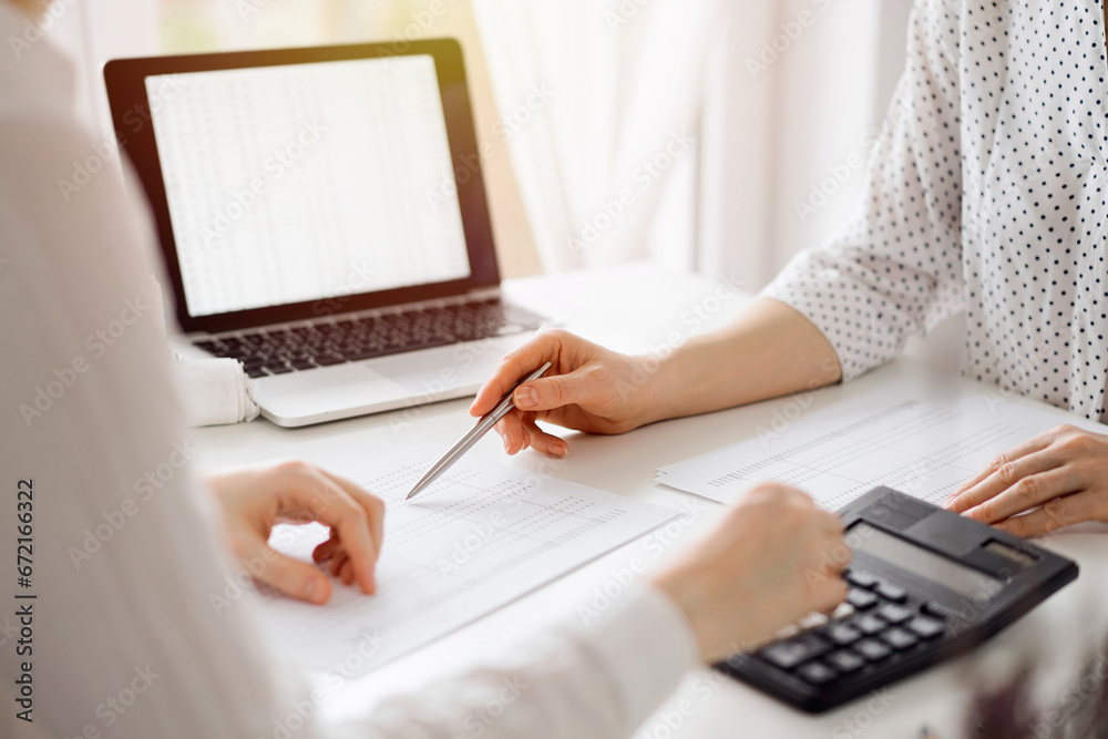 Accountant using a calculator and laptop computer for counting taxes ...