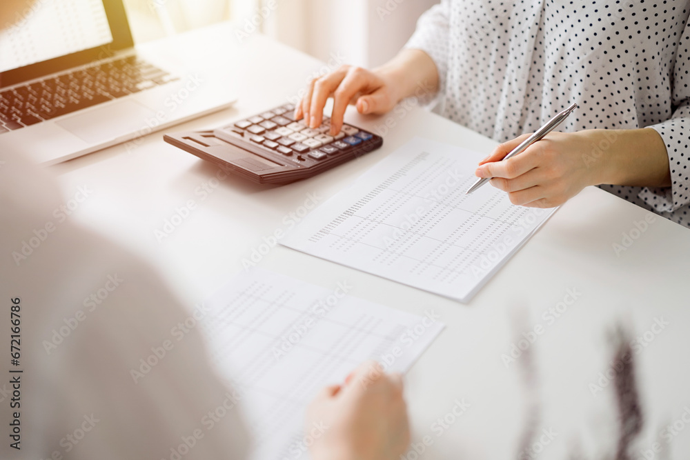 Accountant using a calculator and laptop computer for counting taxes ...
