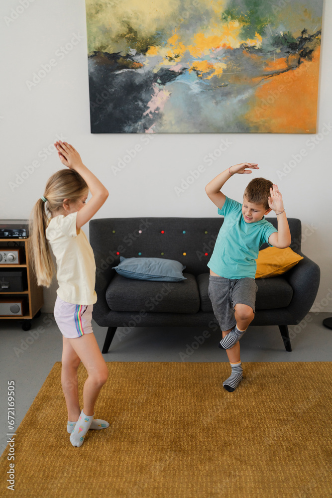 Adorable children looking down while exercising on carpet near sofa set ...