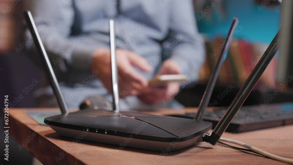 Router stands on the table and distributes Wi-Fi and the man uses this ...