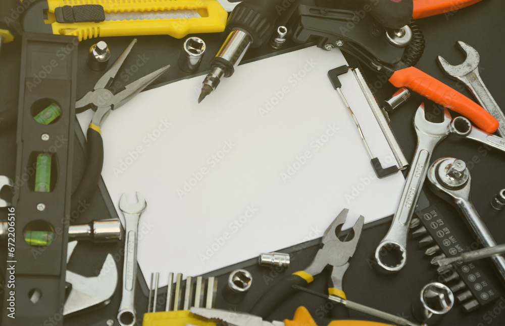 Handyman tool kit on black wooden table with copy space in blank paper ...