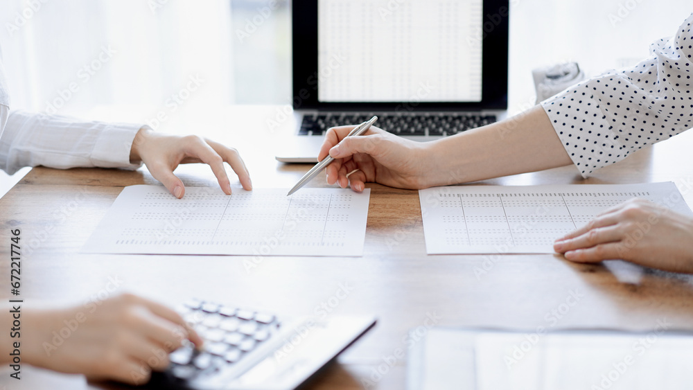Woman accountant using a calculator and laptop computer while counting ...