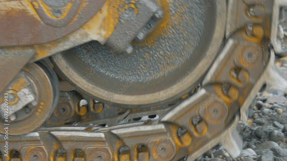 Close-up of heavy excavator tracks flattening the rocky ground at the ...