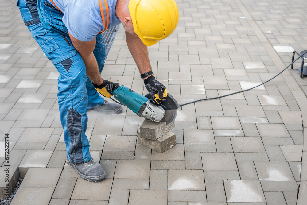Laying interlocking paving. A worker sawing the paving stone with an ...